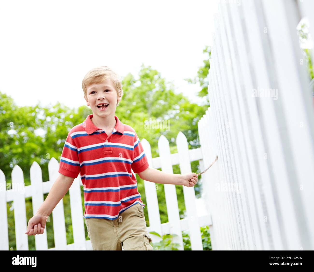 Stick, running and playful with kid and picket fence for fun, break and ...