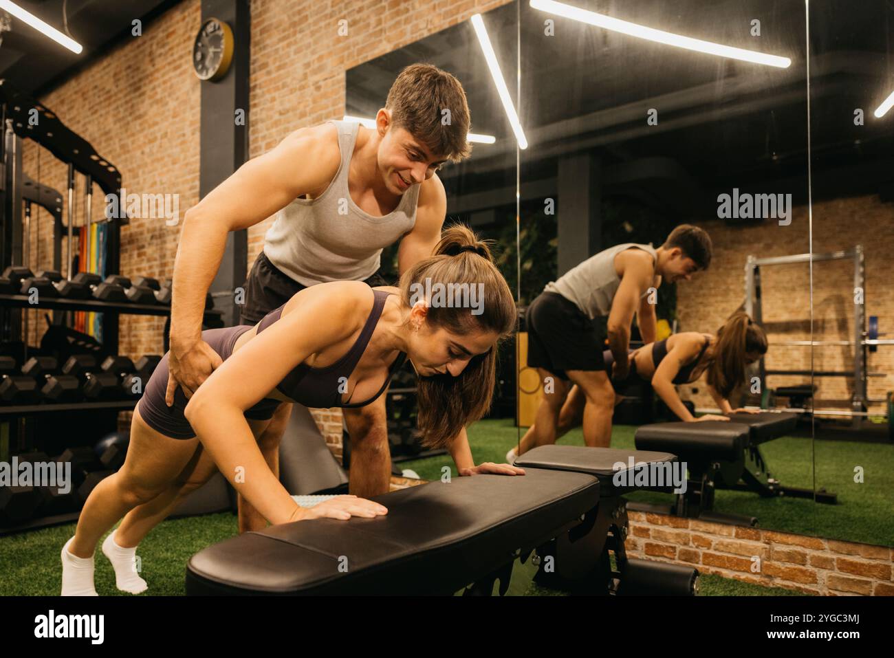 A personal trainer assists a woman with her fitness routine in a ...