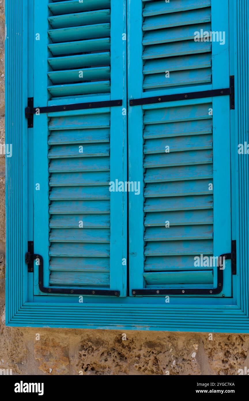 Colorful blue shutters frame a textured stone wall, showcasing charming ...