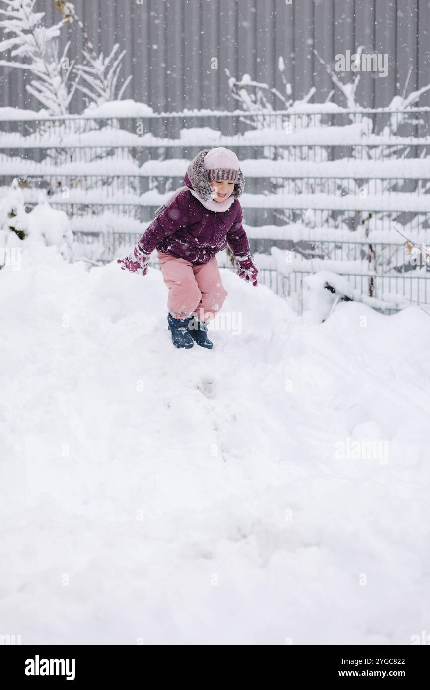 Little girl wearing a cozy winter outfit, happily exploring deep snow ...
