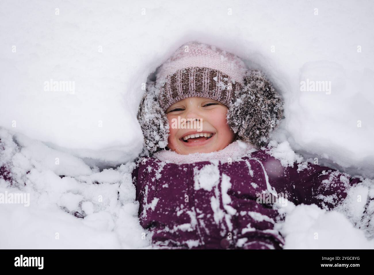 Little girl covered in snow, laughing and playing. A perfect scene of ...