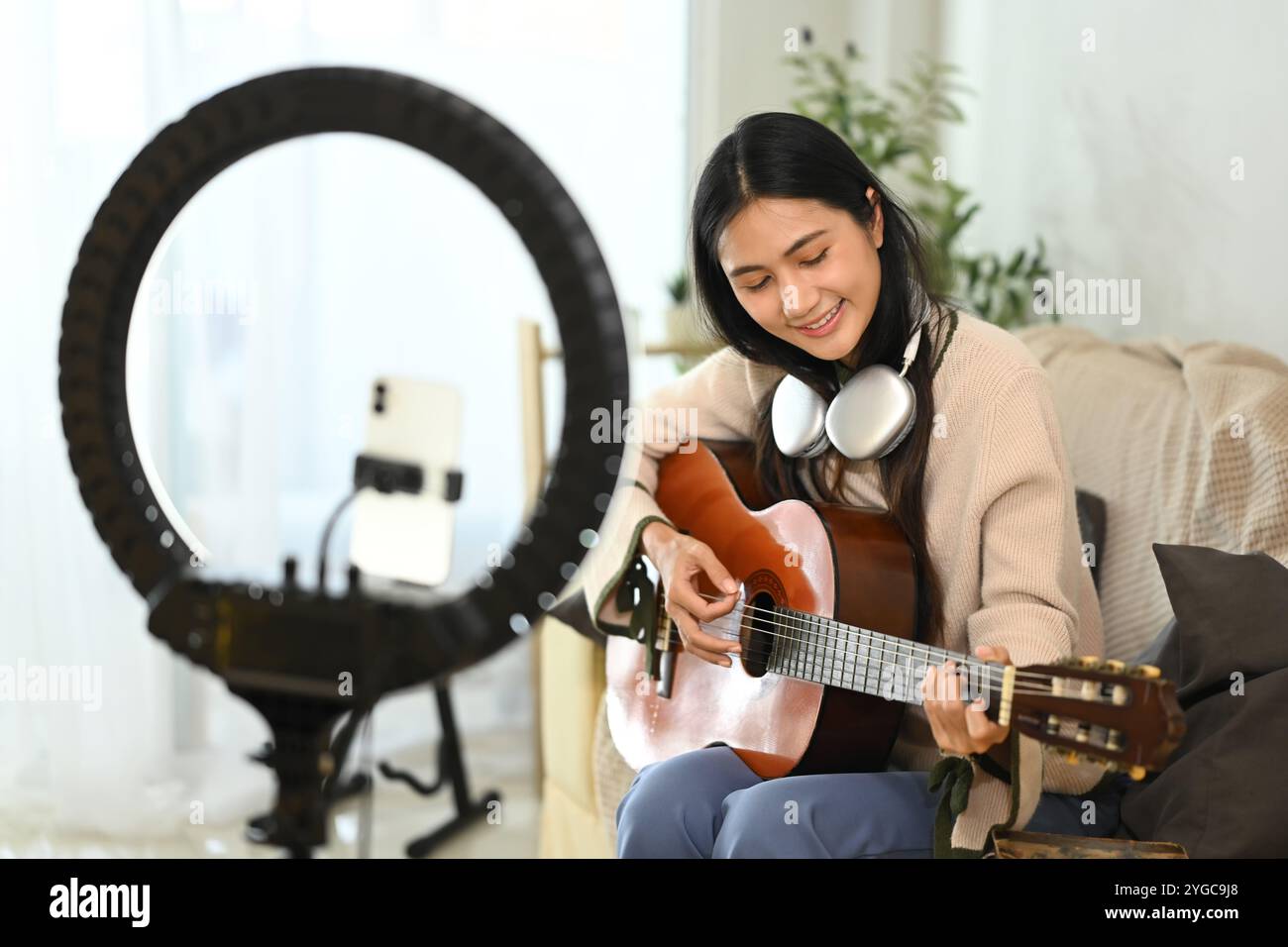 Smiling female music influencer recording video tutorial on playing ...