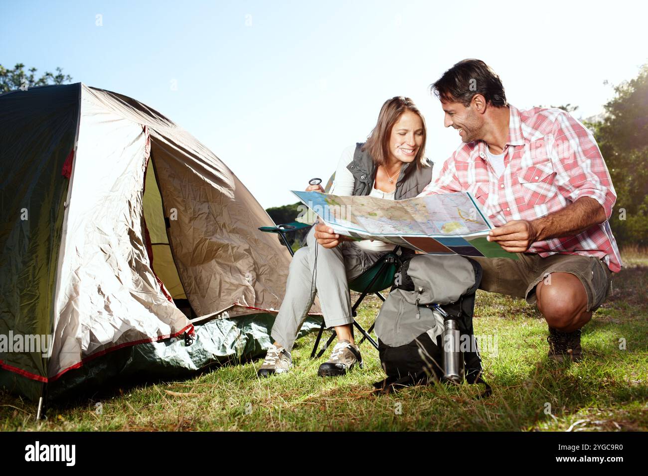 Couple, reading and map for camping by tent on adventure with teamwork ...