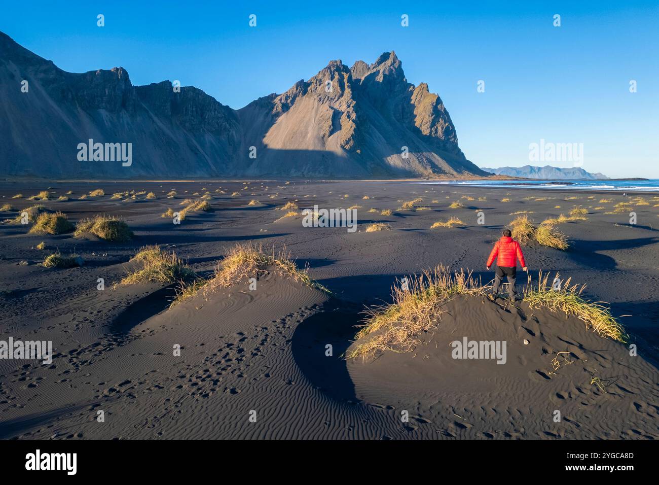 Aerial view of a person admiring the black sand dunes in front of ...