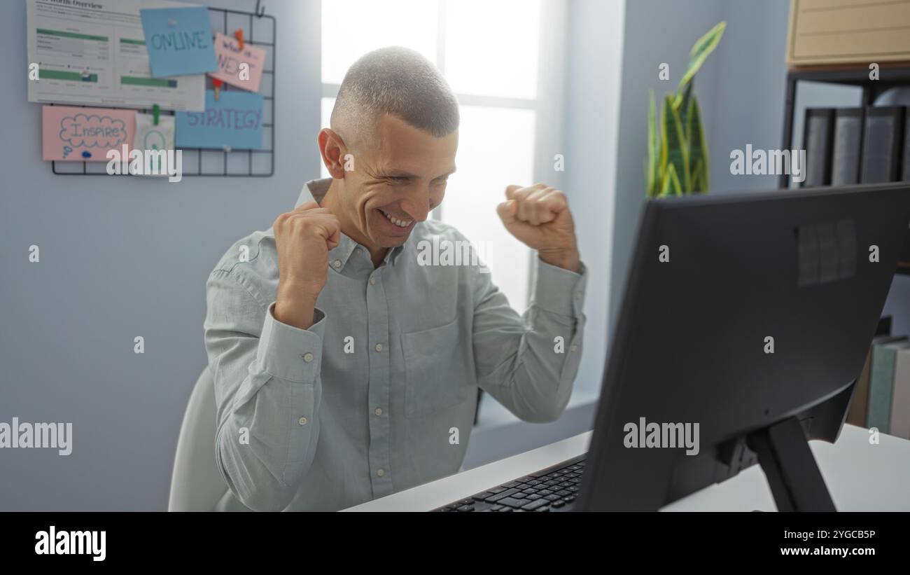 Young man celebrating in an office setting with hands raised in ...