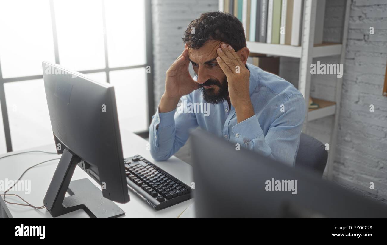 Stressed young hispanic man working indoors in an office room, focusing ...