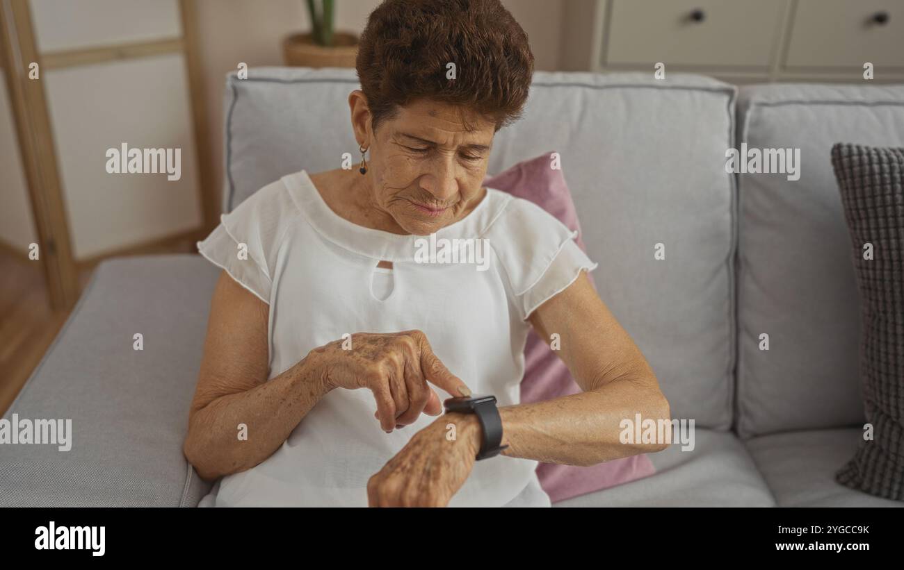 Elderly hispanic woman with short hair sitting indoors on a couch in a ...