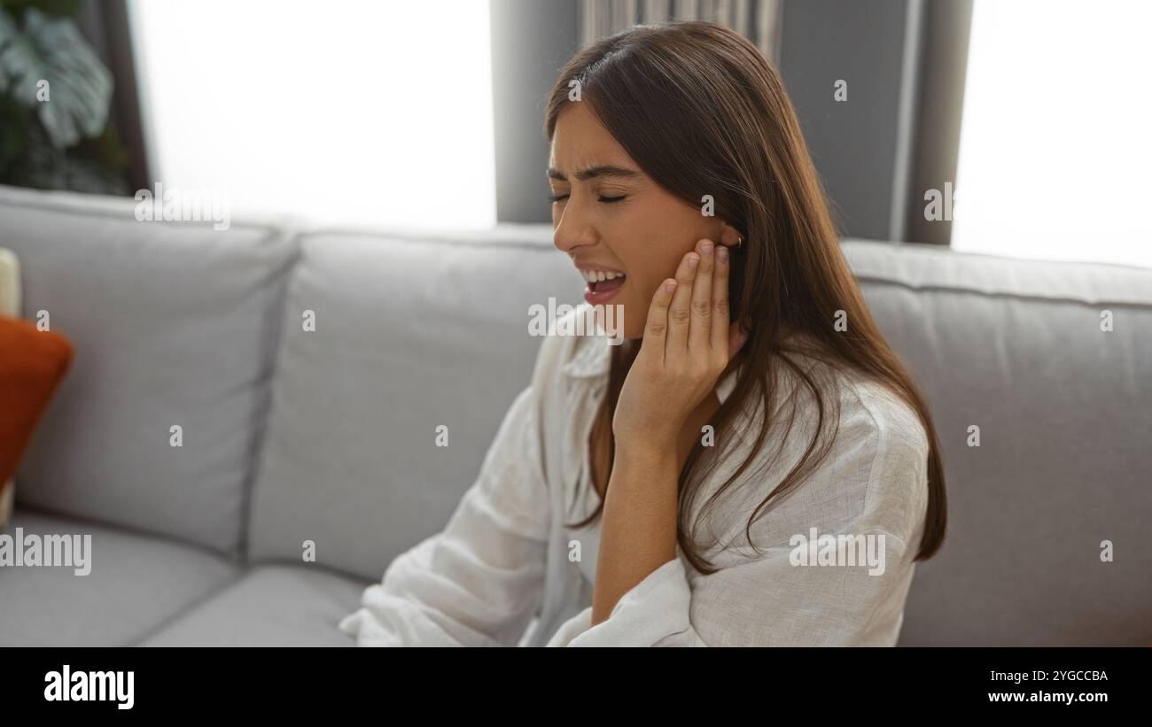 Young woman suffering indoors holding her cheek with a painful ...