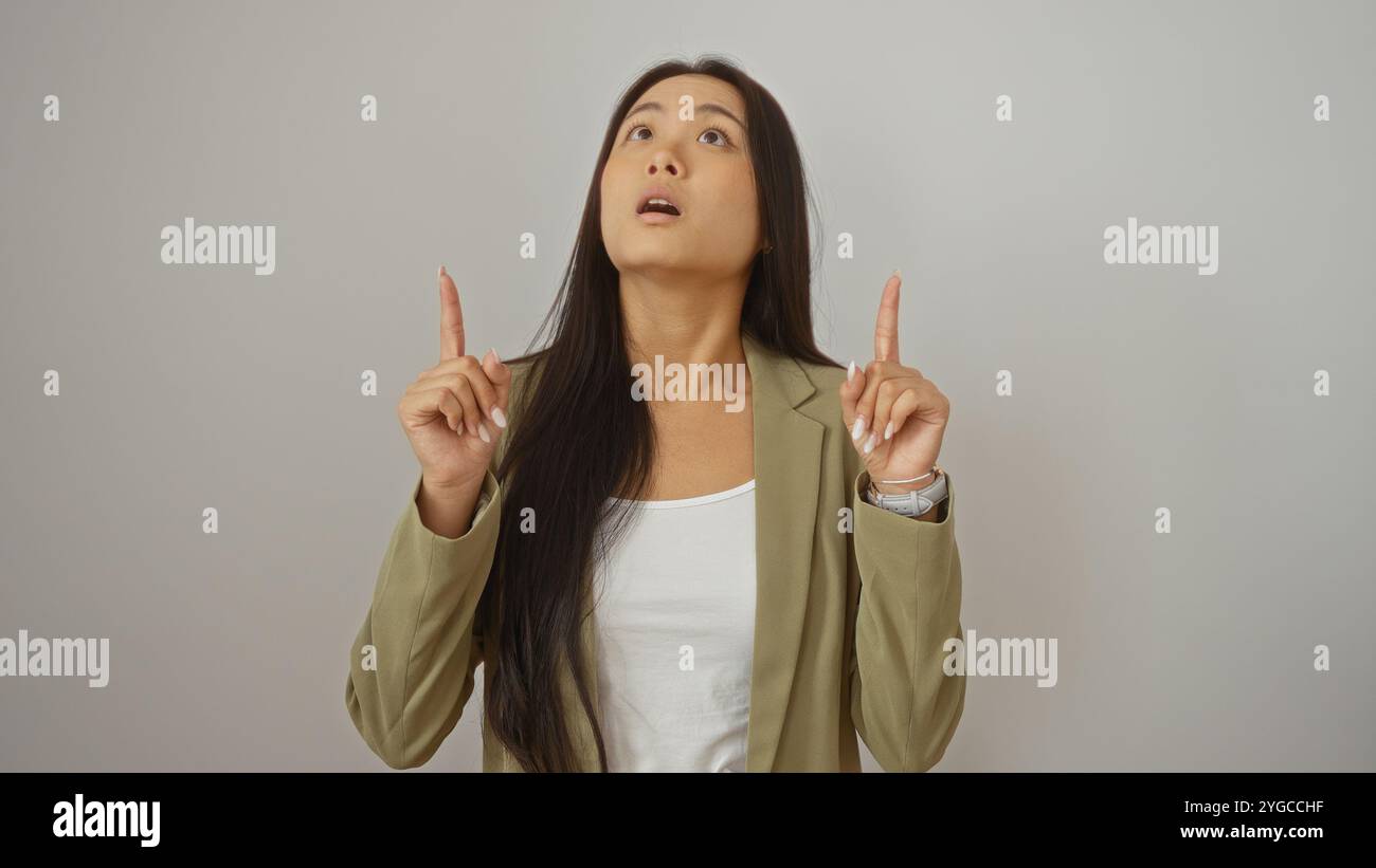 Attractive young chinese woman in blazer pointing upwards over isolated ...