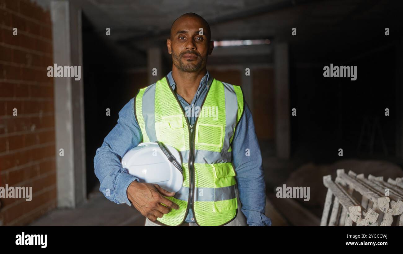 Man wearing reflective vest holding safety helmet inside construction ...