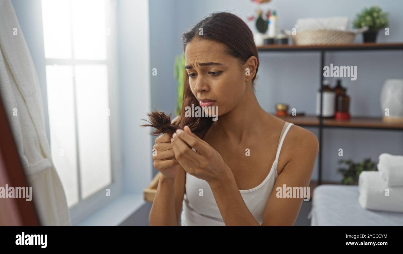 Young woman examining her hair in a spa salon wellness room, showing concern inside an indoor ...