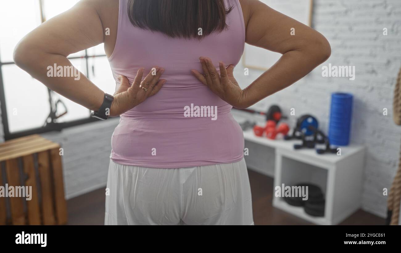 Mature hispanic woman with short hair seen from behind at a gym with ...
