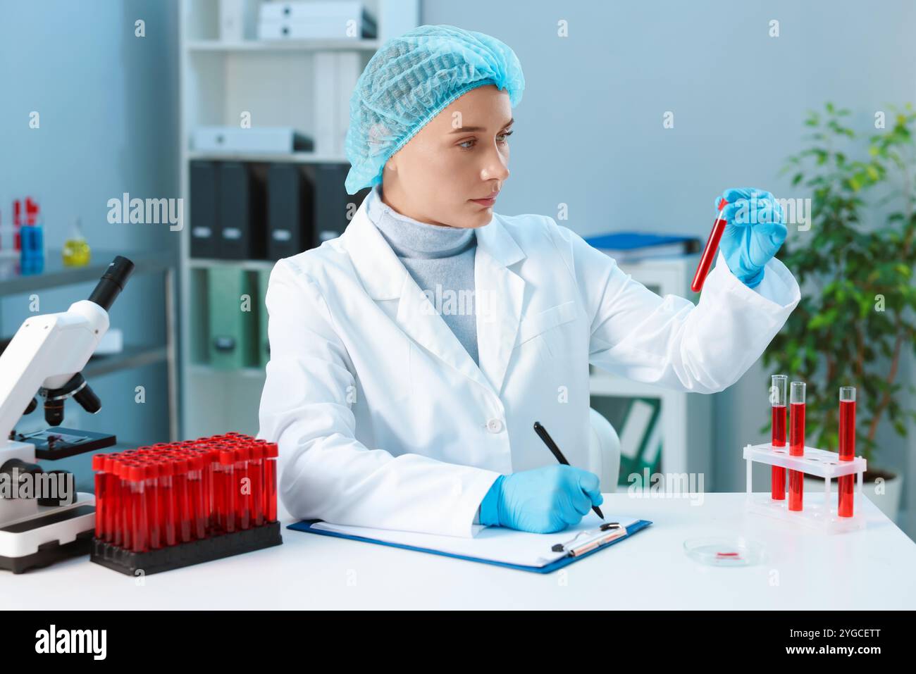 Laboratory testing. Doctor with blood sample taking notes at table ...