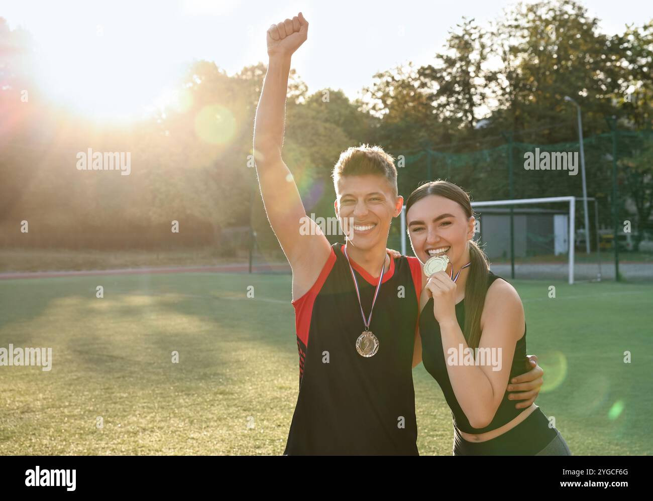 Portrait of happy winners with medals at stadium on sunny day. Space ...