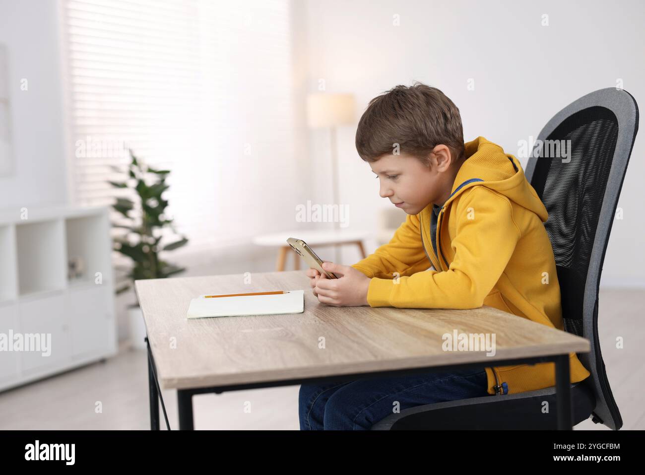 Boy with incorrect posture using laptop at wooden desk indoors Stock ...
