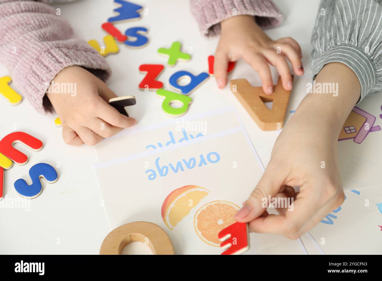 Speech therapist teaching little girl alphabet with different letters ...