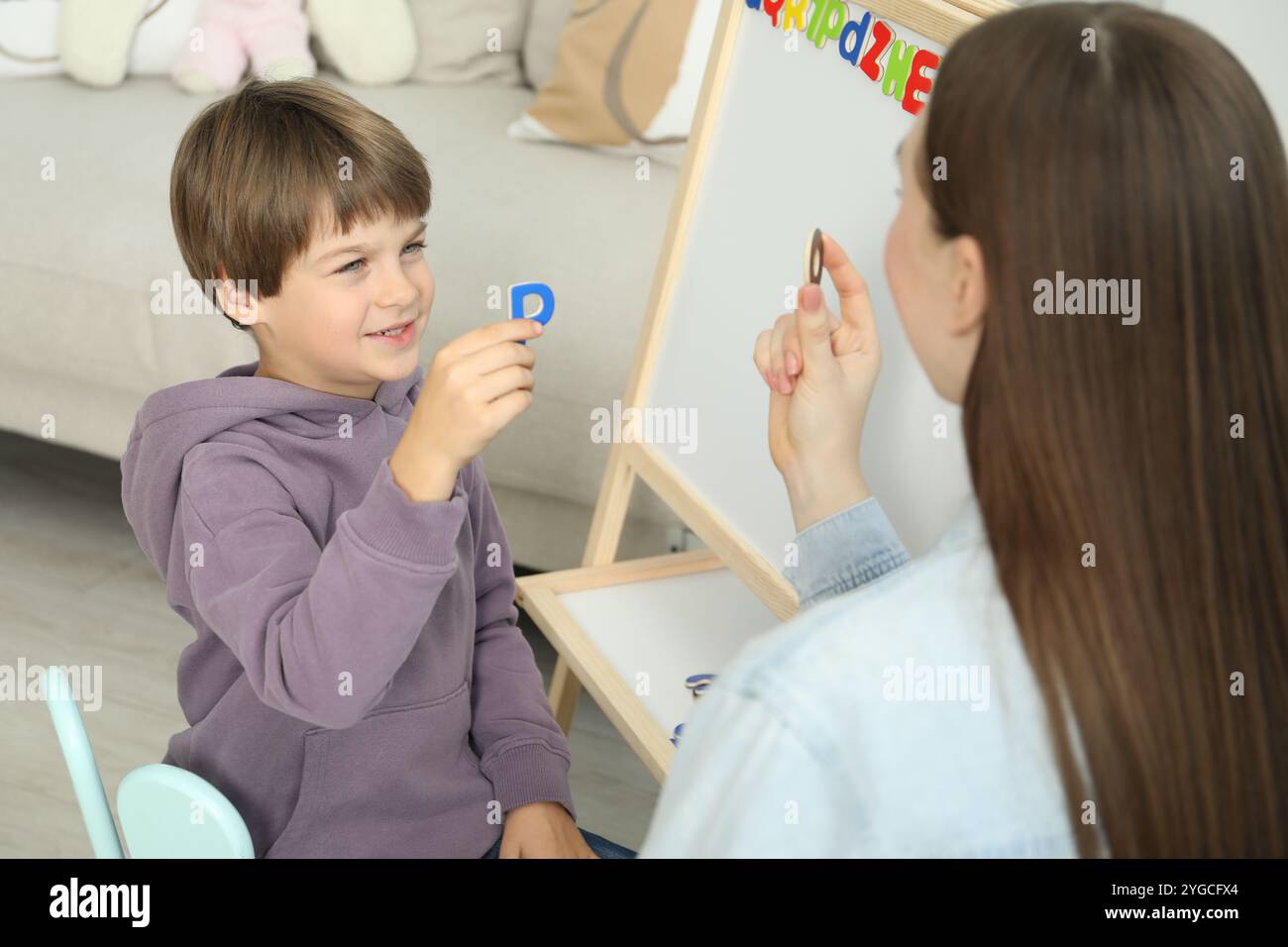 Speech therapist teaching little boy alphabet with magnetic letters ...