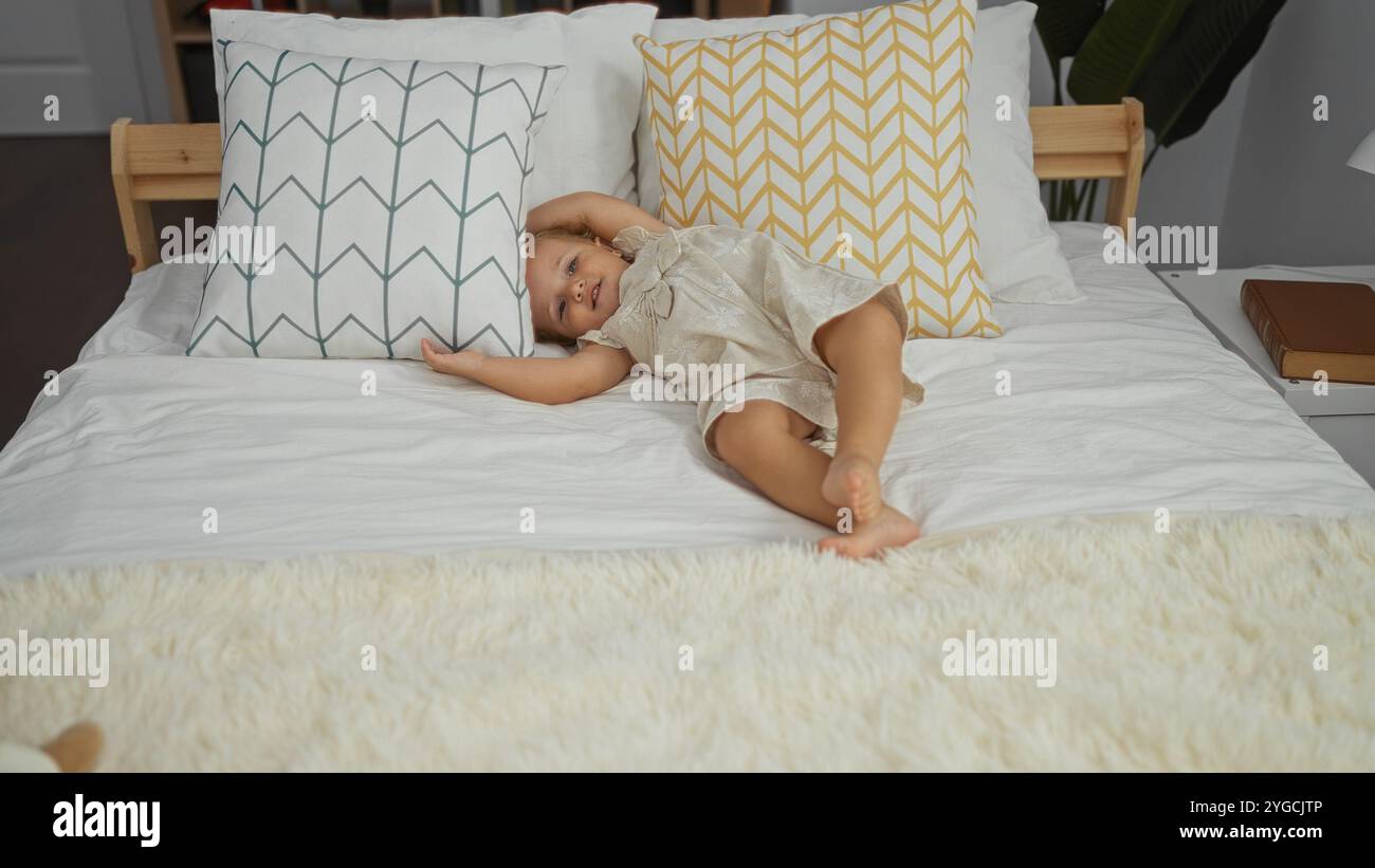 Toddler girl lying on bed in cozy bedroom, with pillows and blanket ...