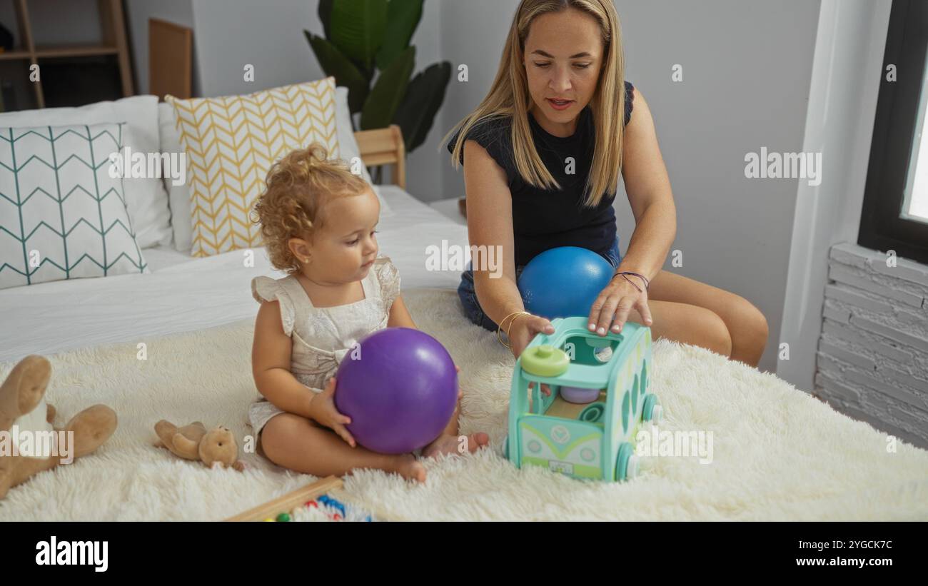 Woman and toddler playing with toys on bed in bedroom at home ...