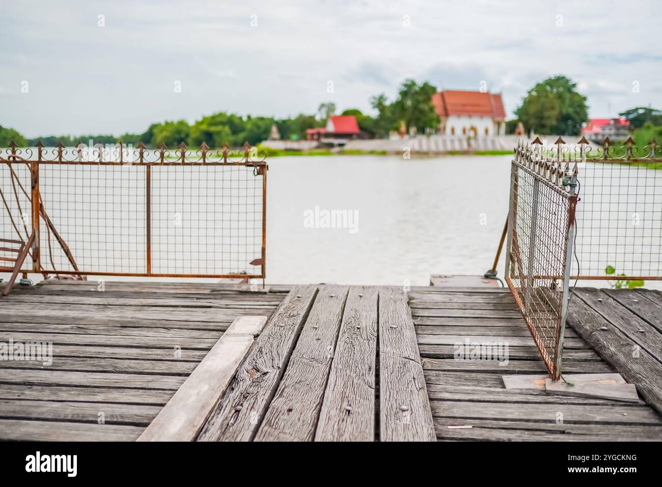 The old wooden dock with decayed iron fences beside a river in Thailand ...