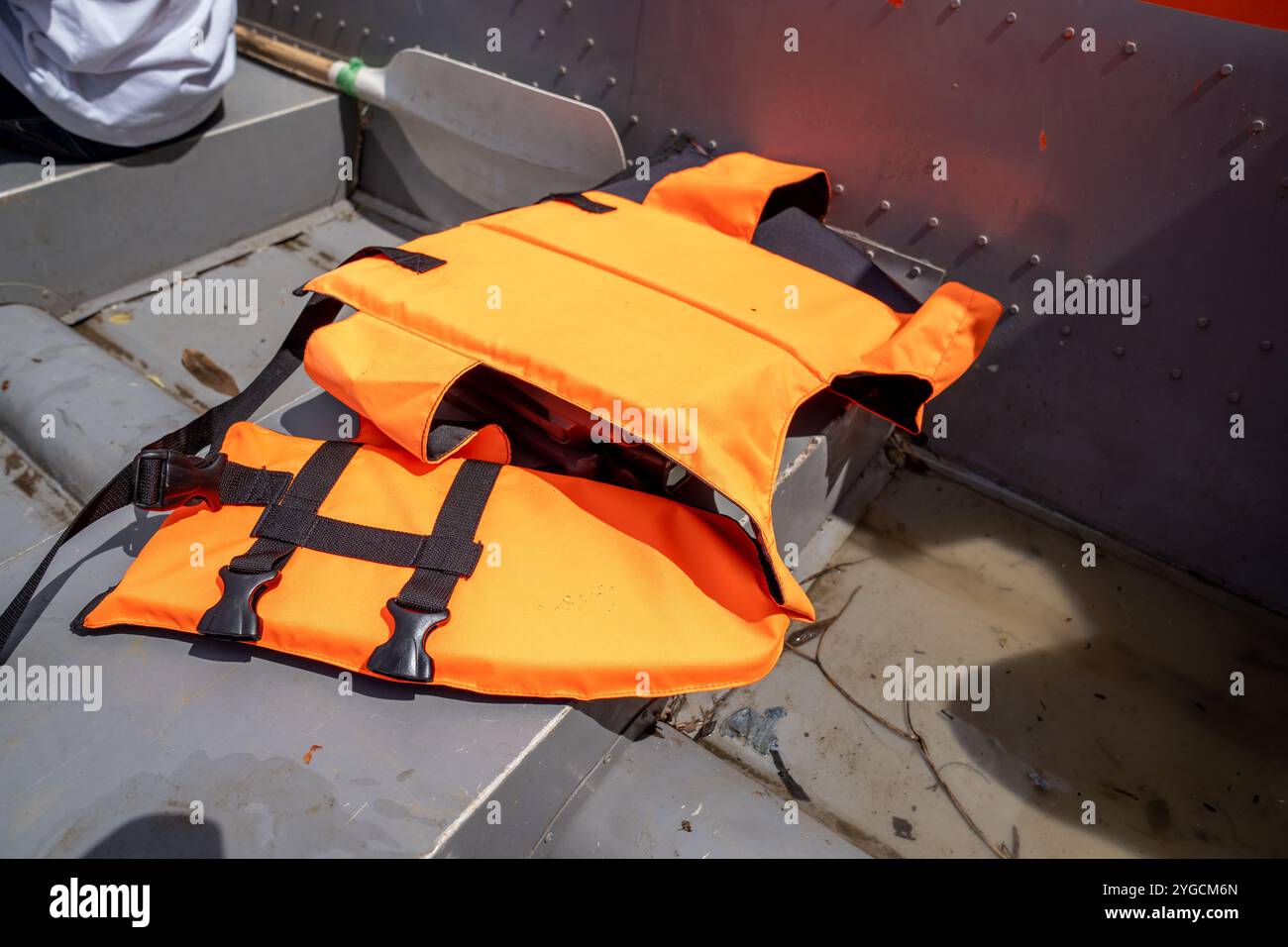 Orange foam life jacket with black belt placed on the seats of the ...