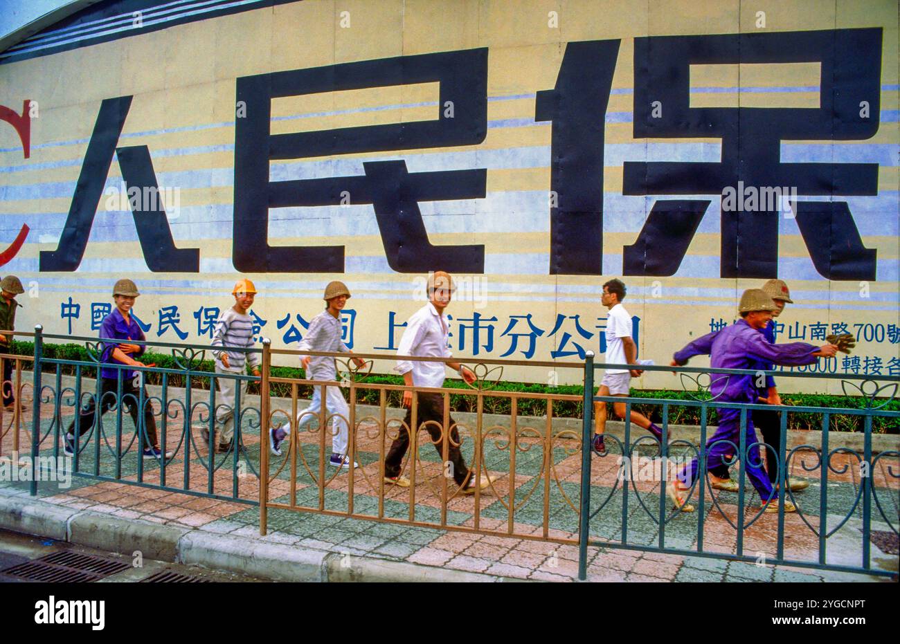 China, Shanghai, construction workers passing a giant character mural ...