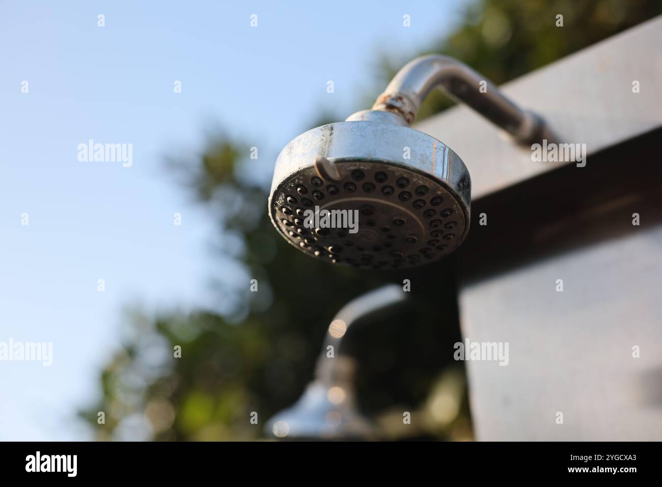 Experience the refreshing feel of an outdoor shower head set against a ...
