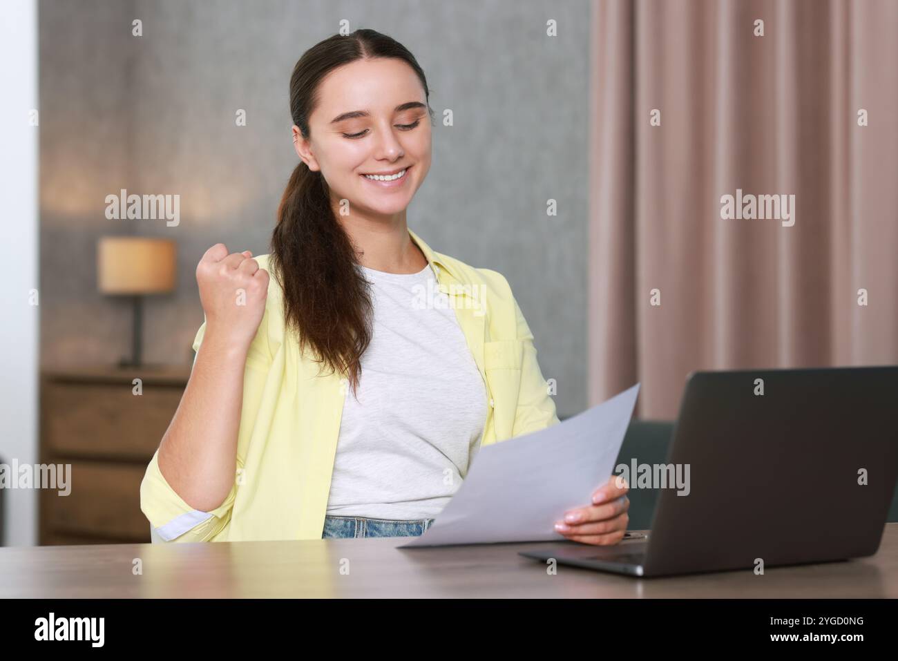 Young student with sheet happy about her good exam result at workplace ...