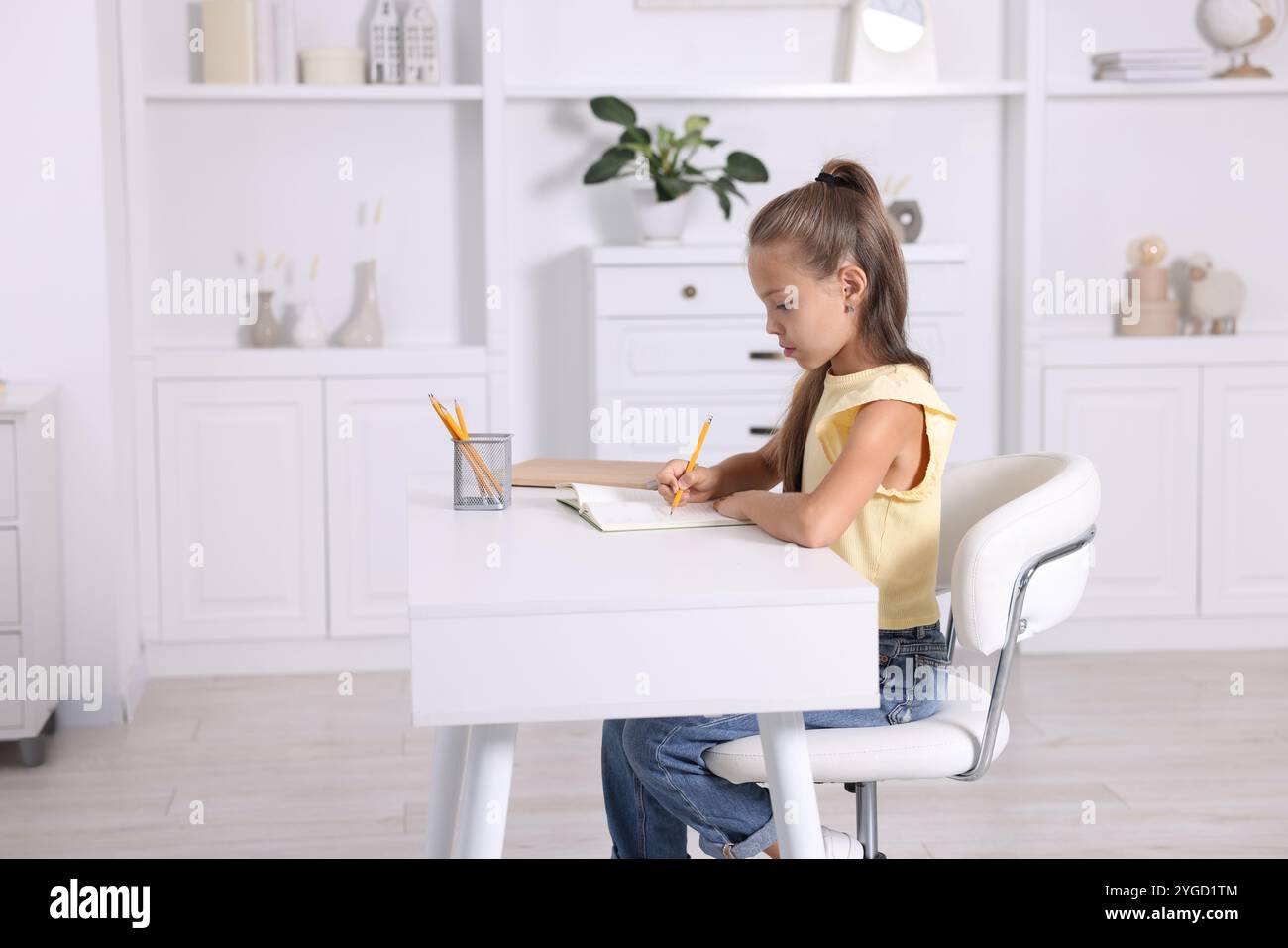 Girl with correct posture doing homework at white desk indoors Stock ...