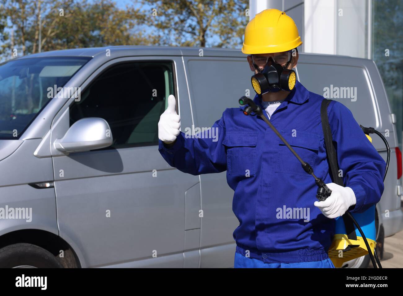 Pest control worker with spray tank showing thumbs up outdoors Stock ...