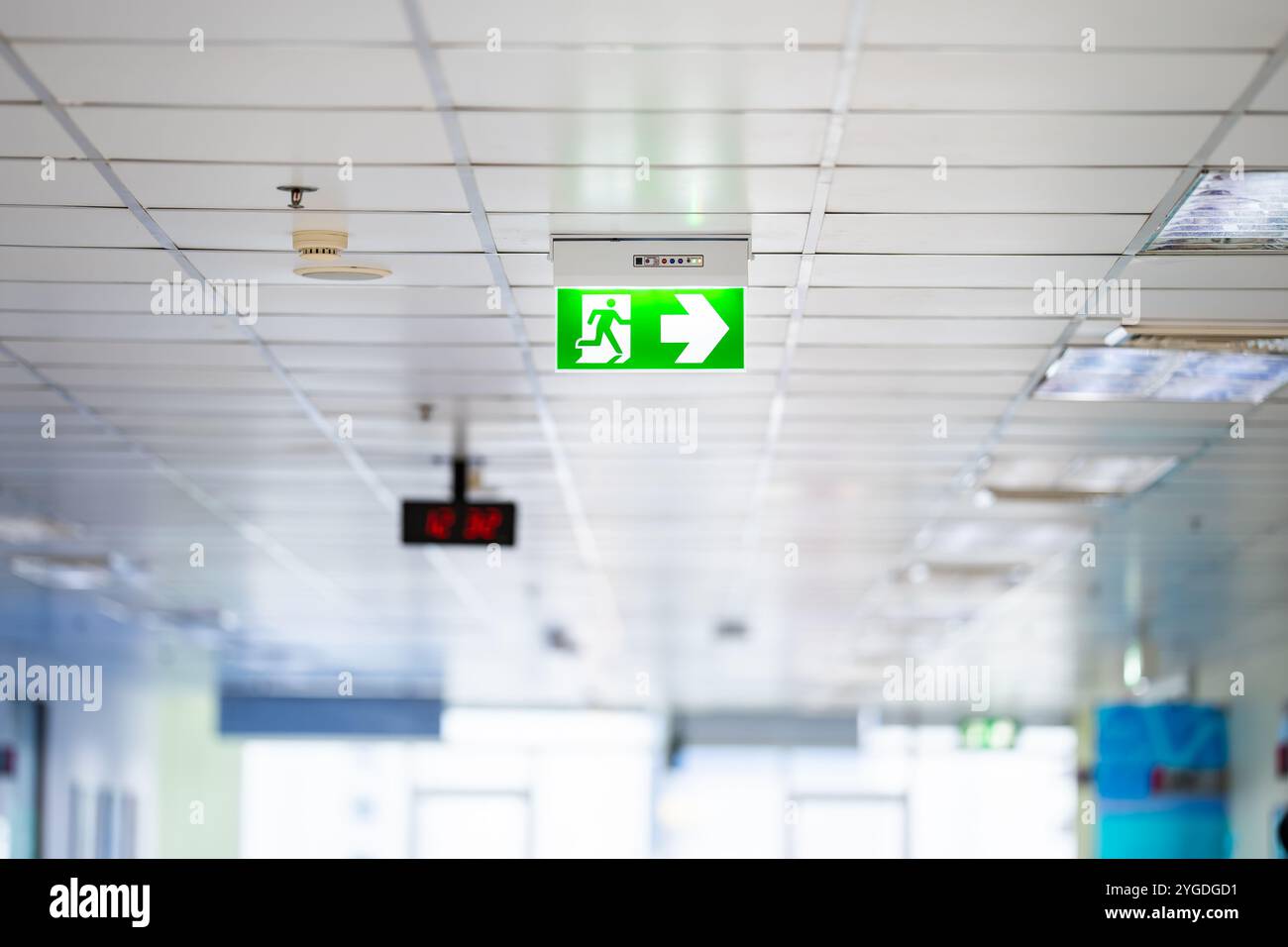 Green White light neon sign depicting a fire exit with interior mirror ...