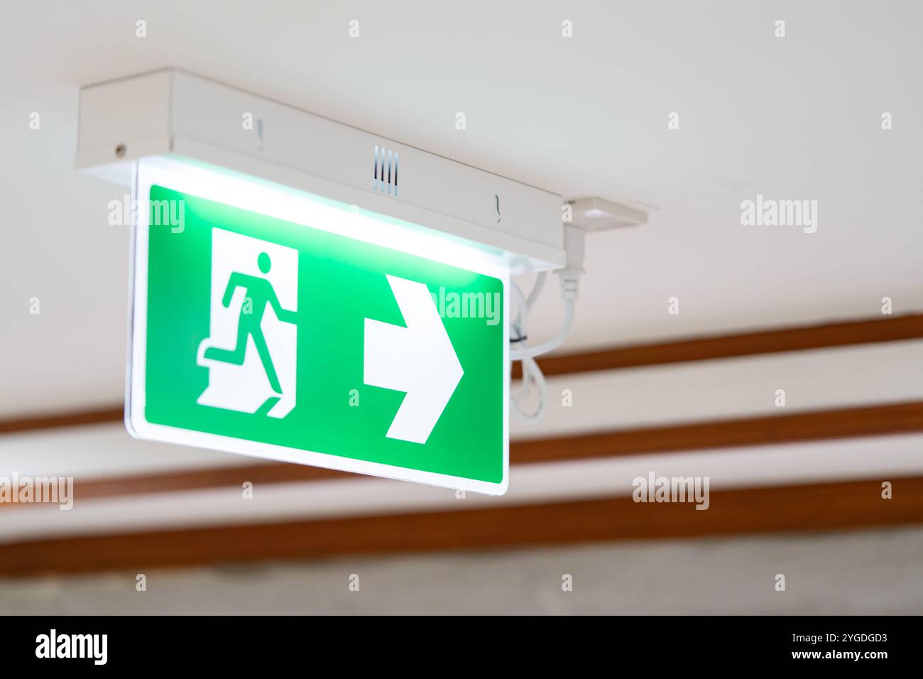 A Arrow light box sign of EMERGENCY FIRE EXIT is hung on the ceiling in ...