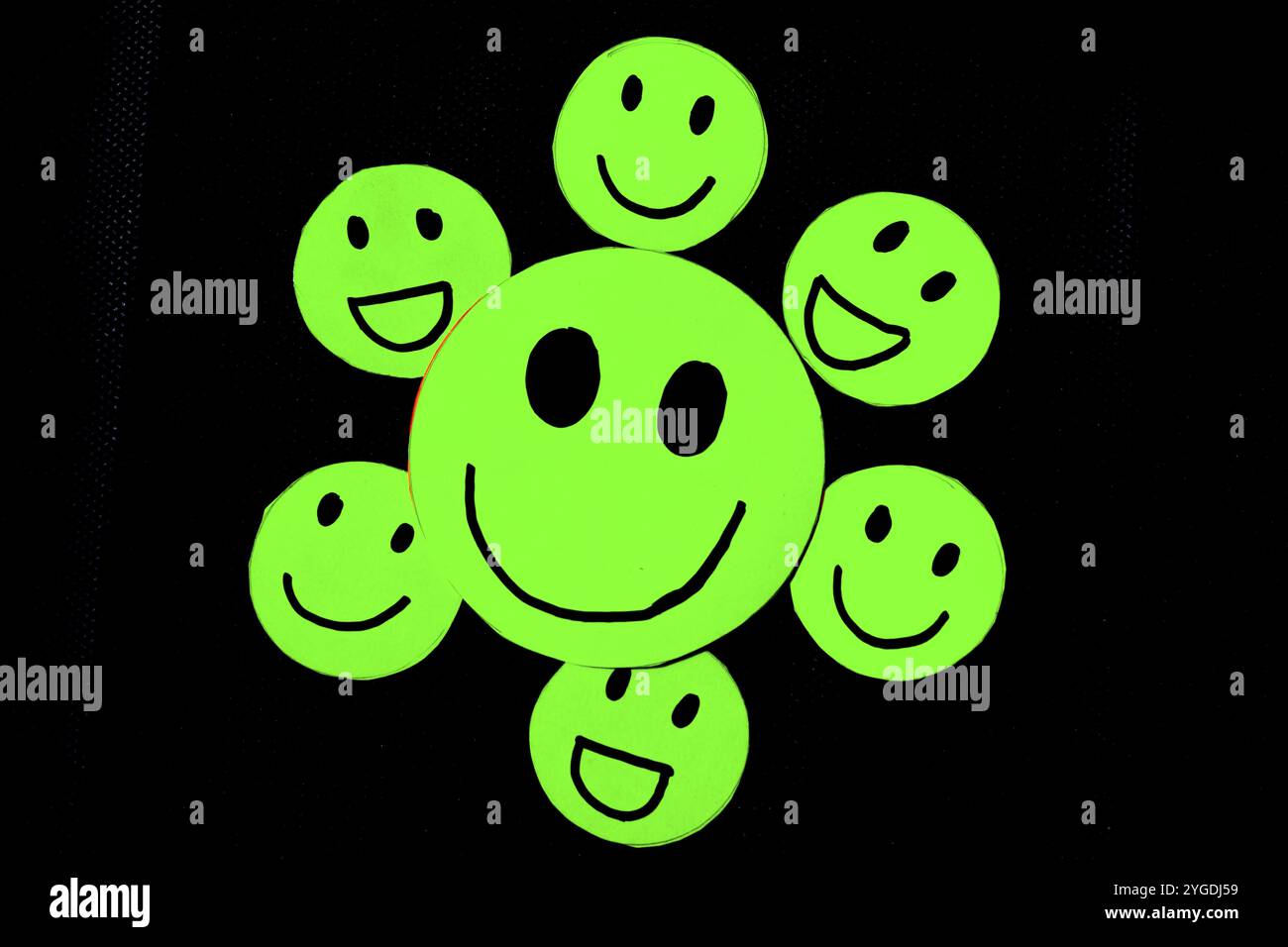 Cutout of green emoticons with smiley face on black background. Concept ...