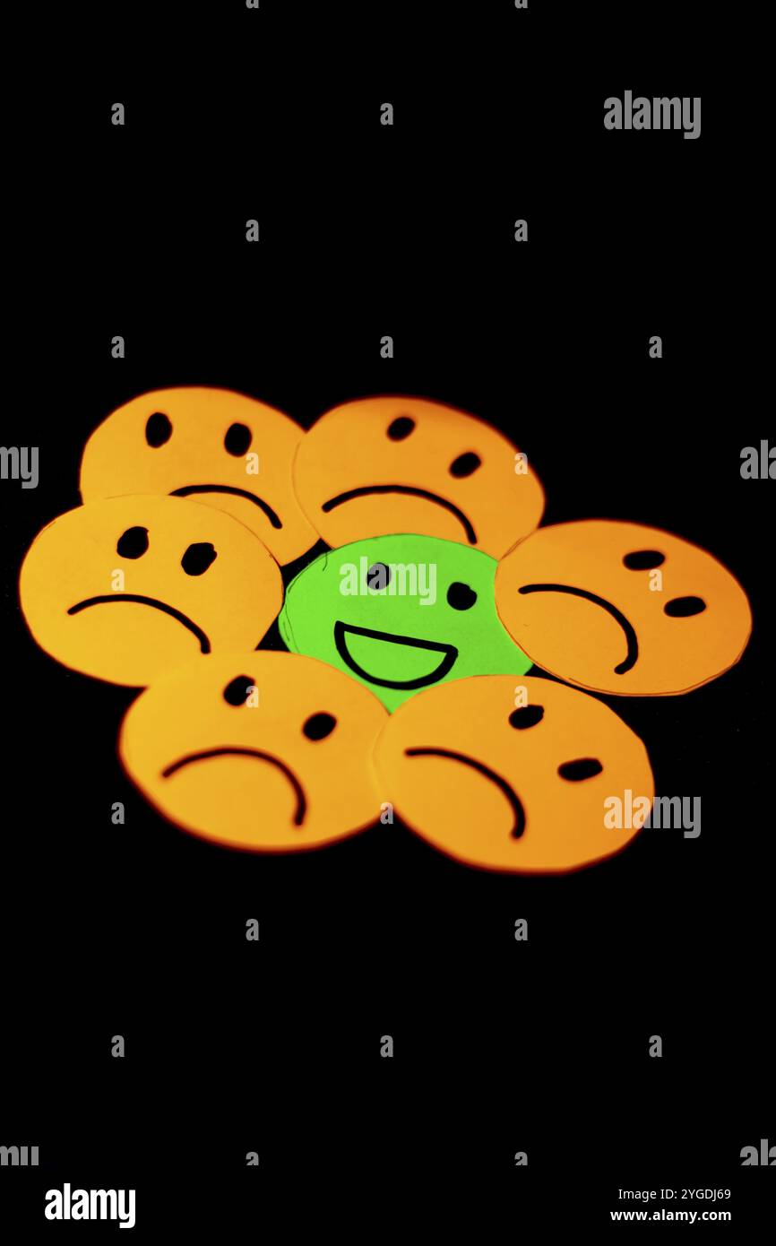 Paper cutouts of sad smileys surrounding a happy smiley. concept of ...