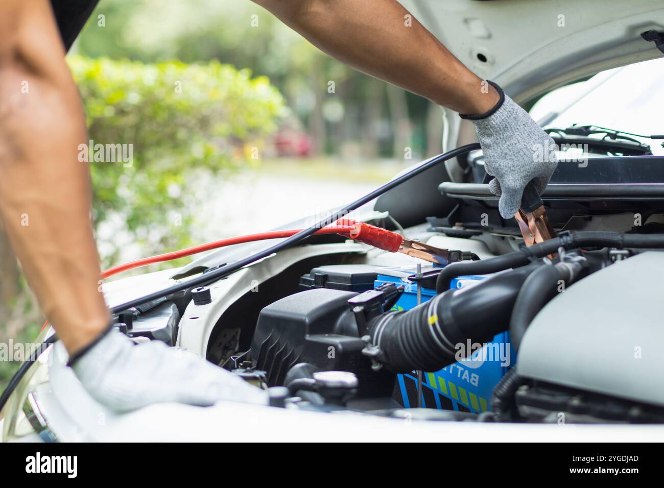 mechanic from the service center is helping to jump start the car ...