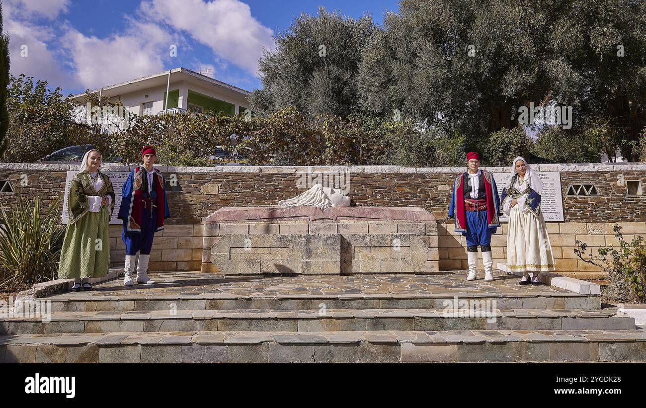 People in traditional Cretan costumes pose in front of a historic wall ...