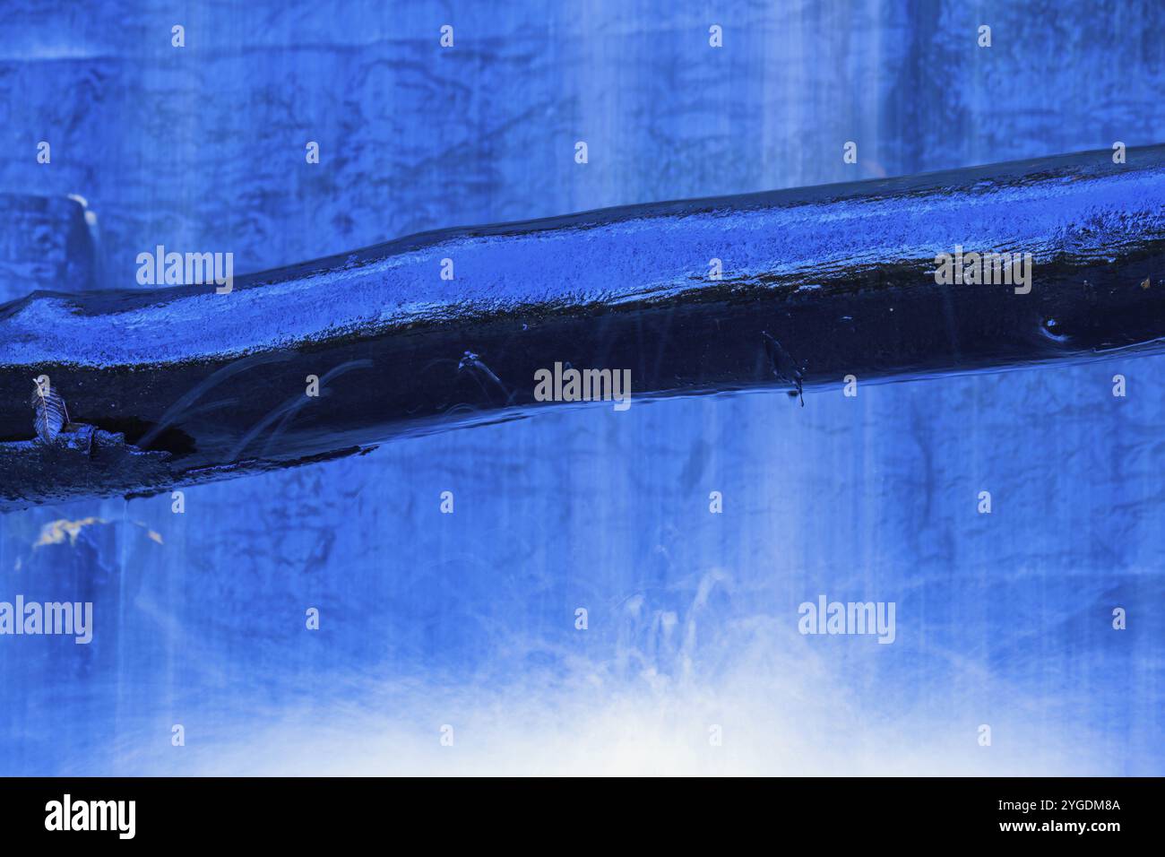 Wet tree log in a waterfall by a rock face Stock Photo - Alamy