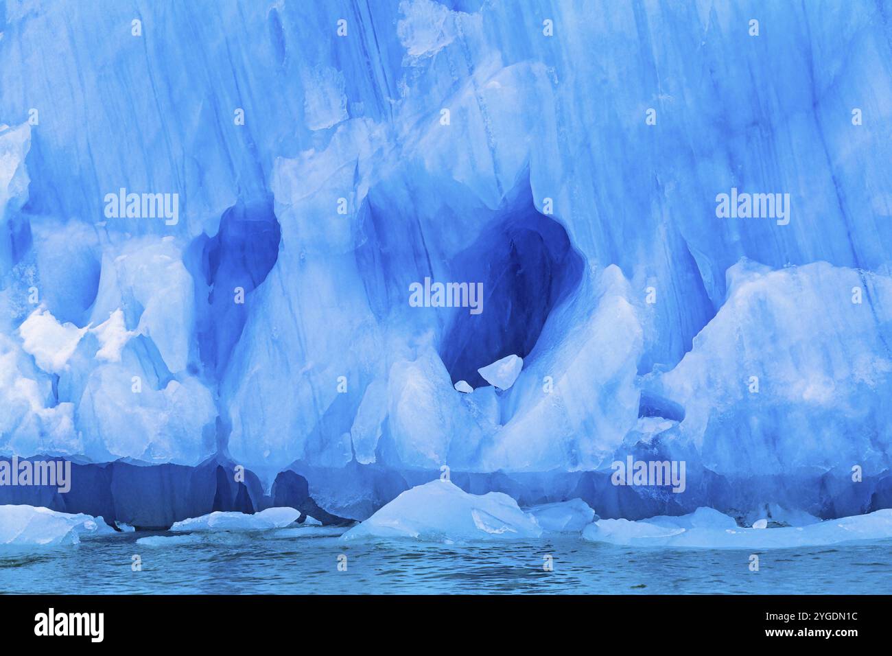 Ice wall with turquoise color and caves on a sea glacier in the Arctic ...