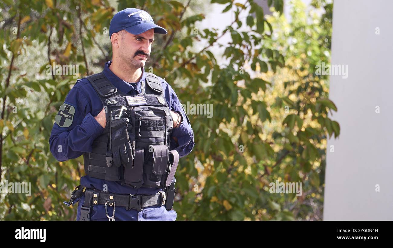 A man in uniform with a tactical waistcoat stands outside in front of a ...