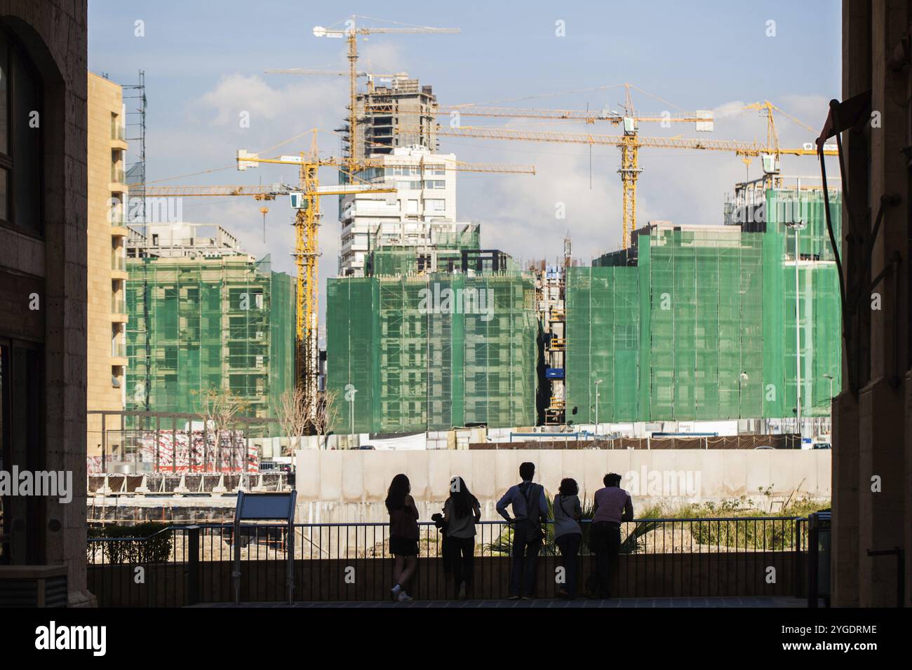 A group of young people look at a building site with numerous ...