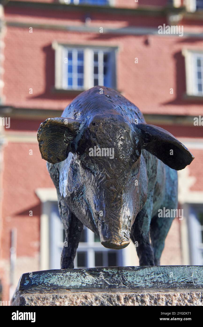 Bronze sculpture of a wild boar in front of a red building with windows ...