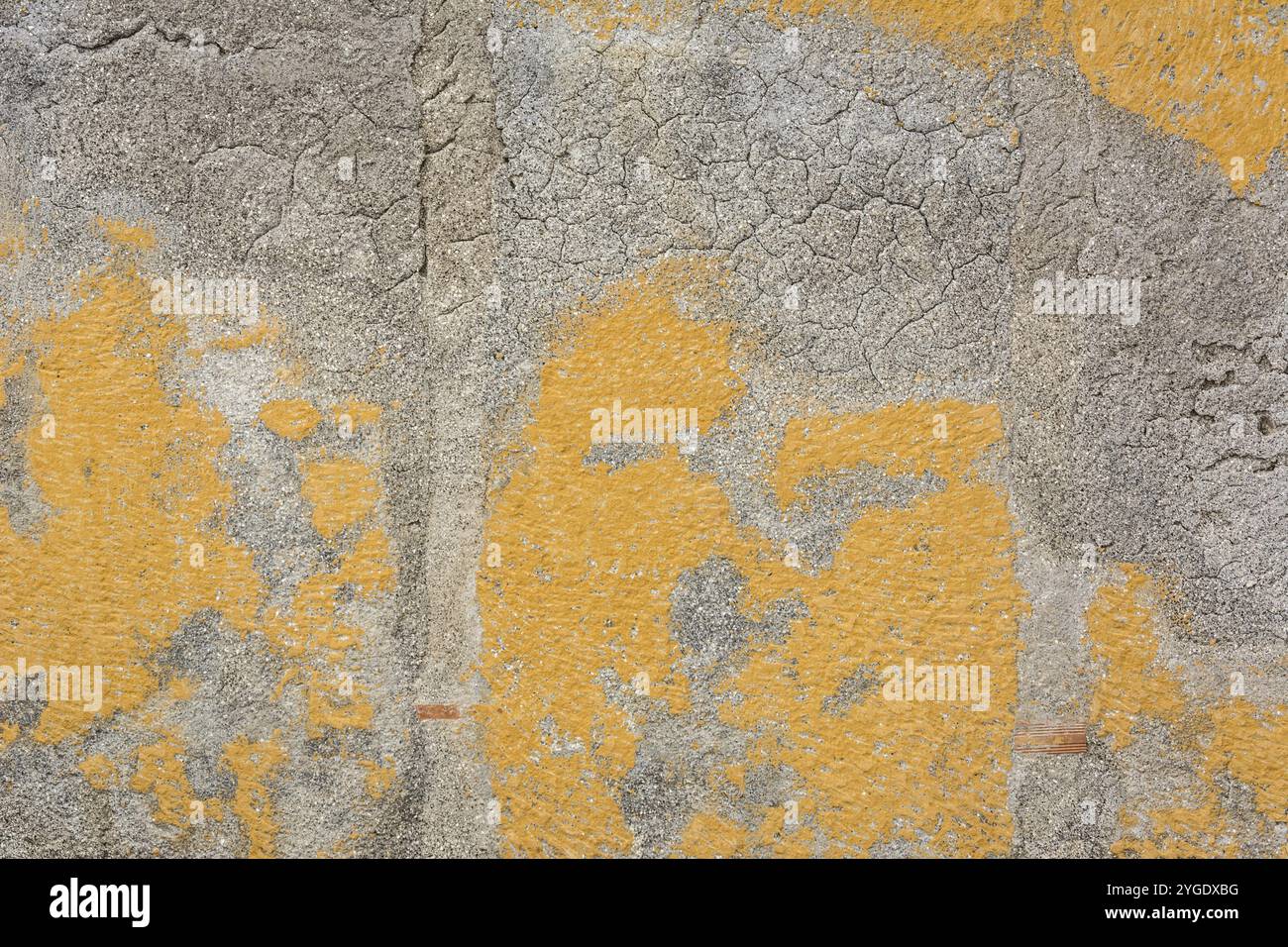 Background weathered concrete wall with partly peeled off yellow paint ...