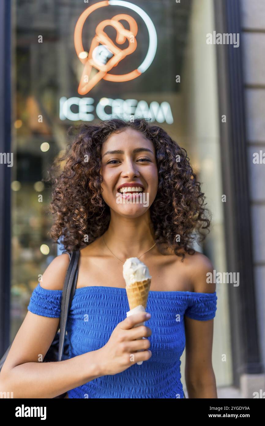 Vertical photo of a happy latin woman holding an ice cream cone ...