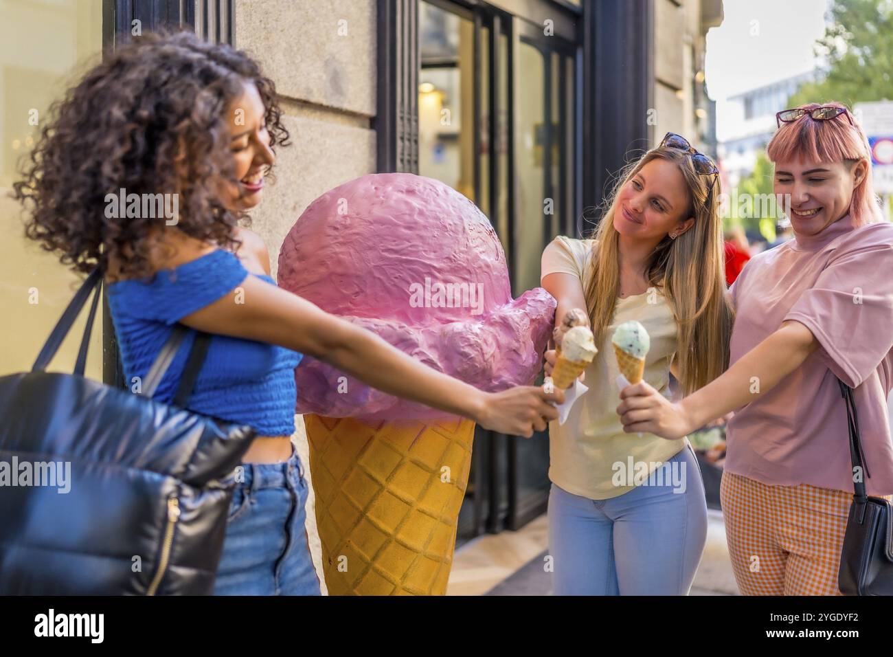 Diverse women having fun eating ice cream next to giant ice cream cone ...