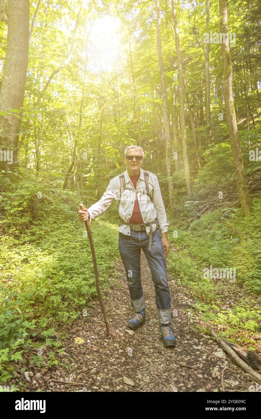 Senior male hiker at the start of his tour on a trail in the forest in ...