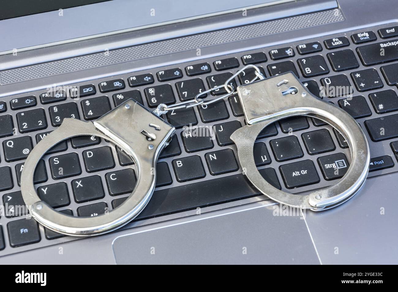 Handcuffs lying on computer keyboard as a symbol for cybercrime Stock ...