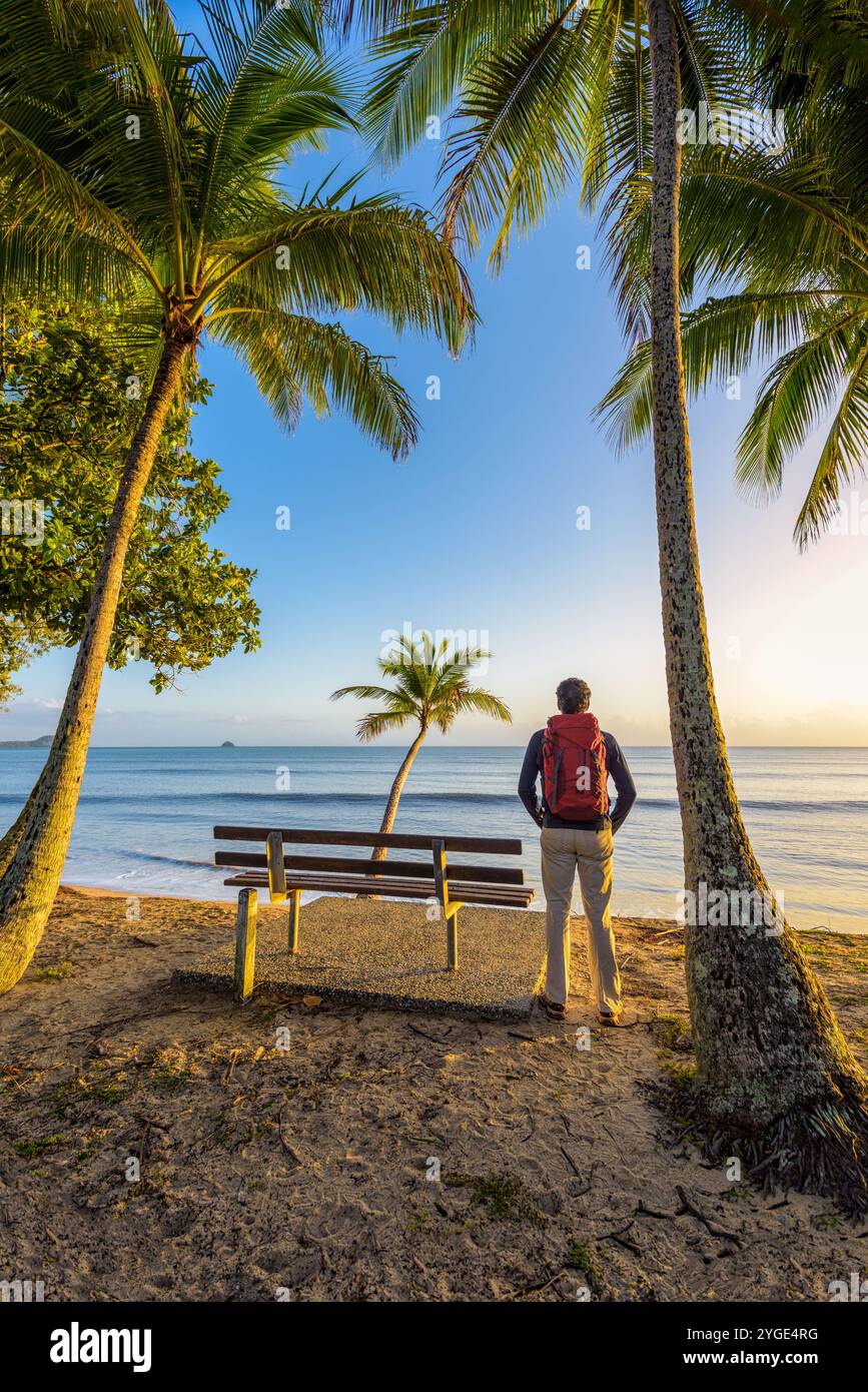 Standing facing the Pacific Ocean a backpacker is framed, on a beach ...