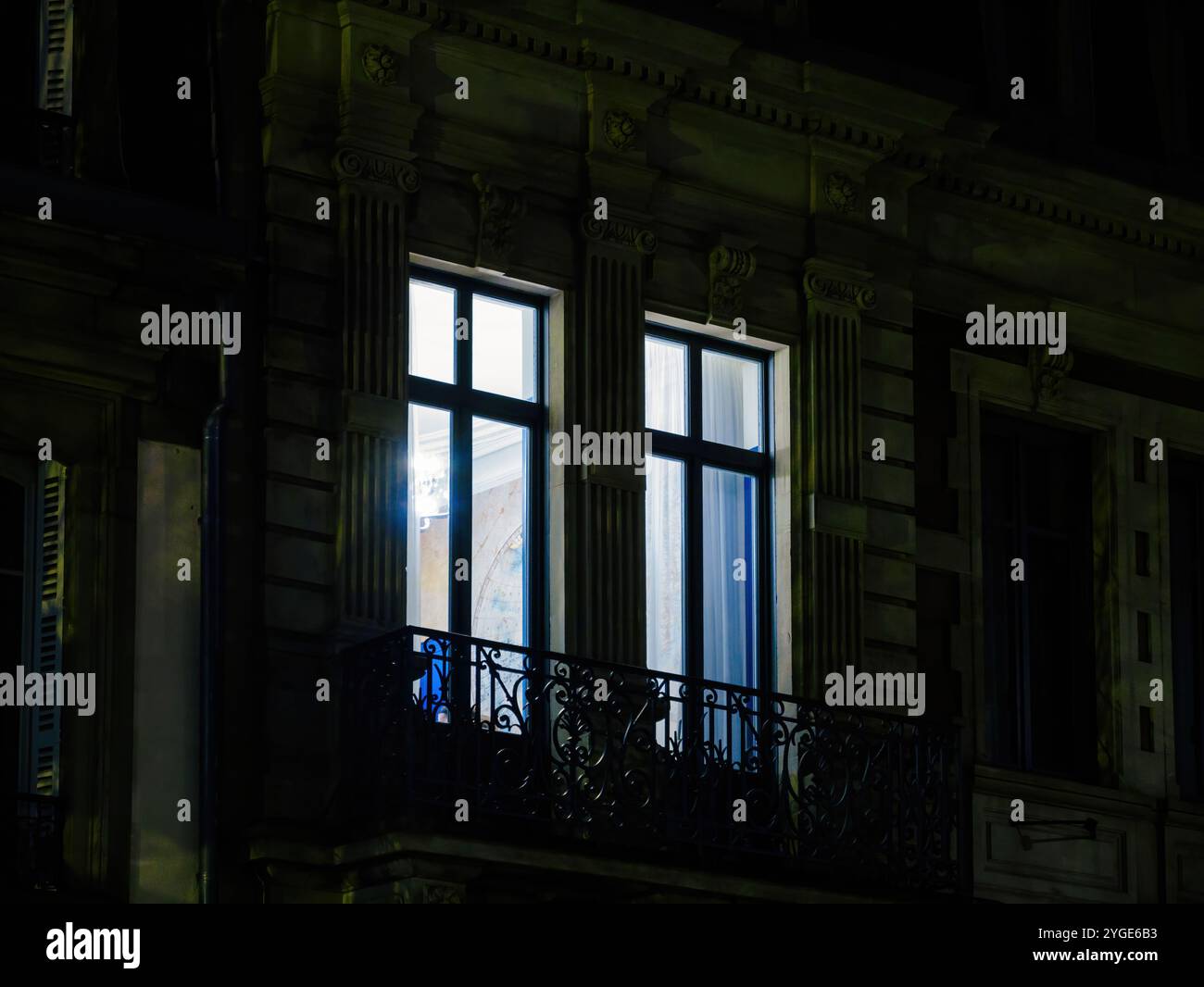 Illuminated window of a luxury apartment with ornate balcony railing at ...