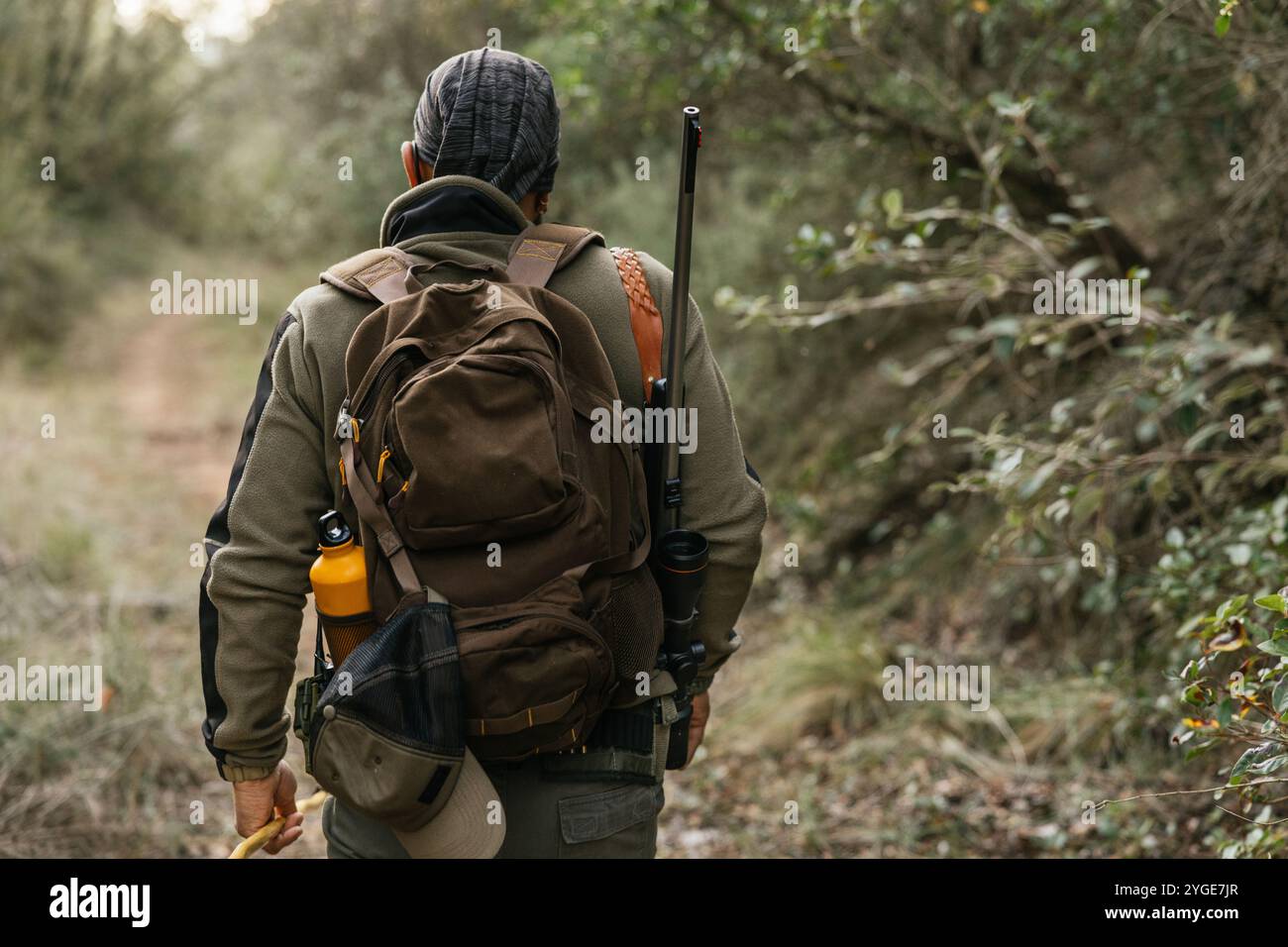 Hunter walking in the woods carrying a rifle and backpack Stock Photo ...
