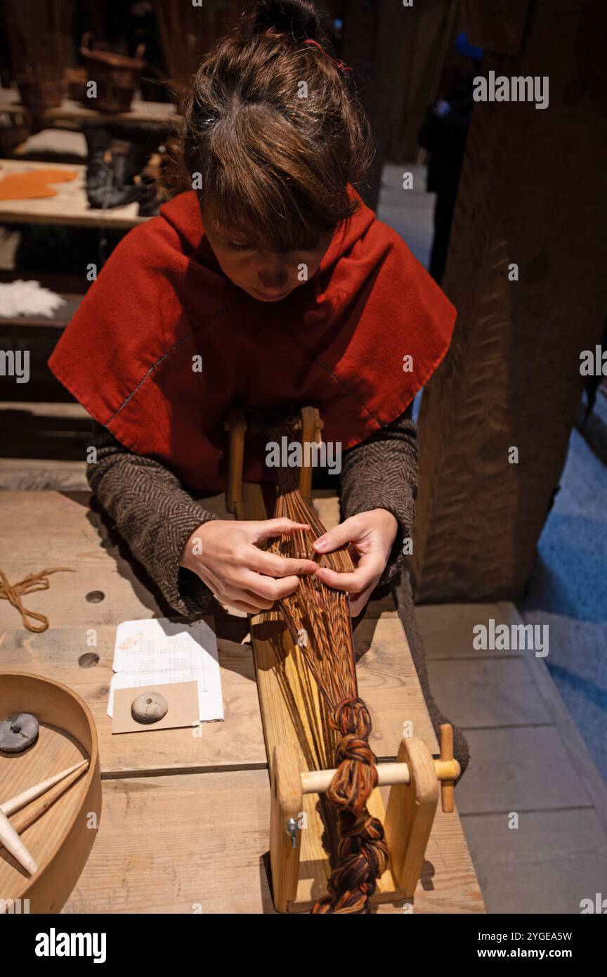 A woman dressed the part of a Viking weaver at her workbench in the ...